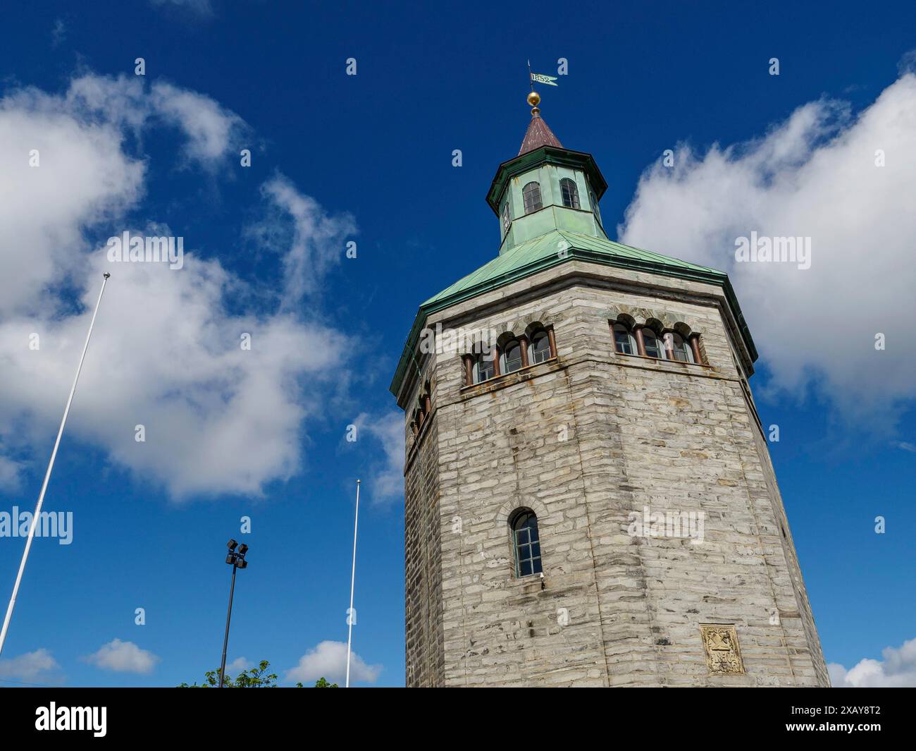 Historic stone tower with clock and flag under a bright blue sky ...
