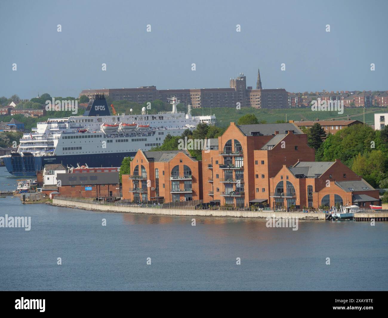 Large ferry in harbour in front of modern brick houses and wider urban ...