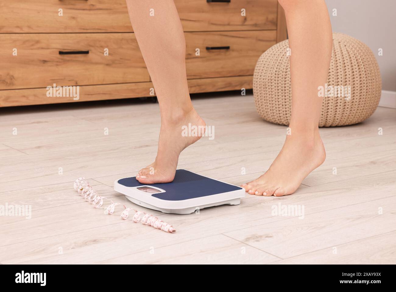 Woman stepping on floor scale and measuring tape at home, closeup ...