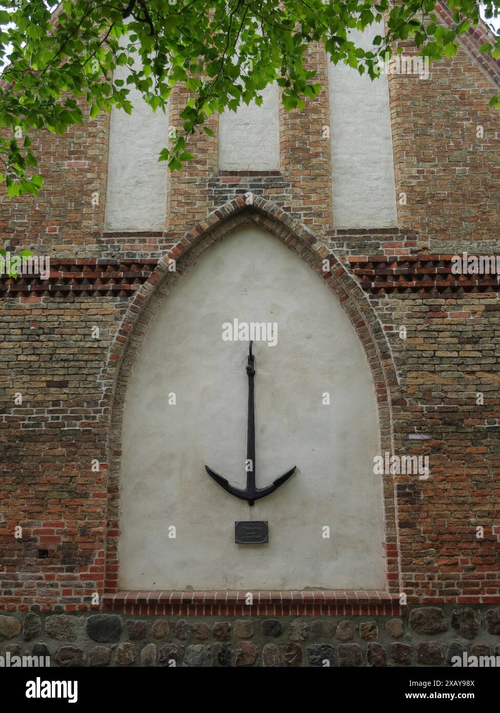 A large black anchor adorns a Gothic brick wall of an old church ...