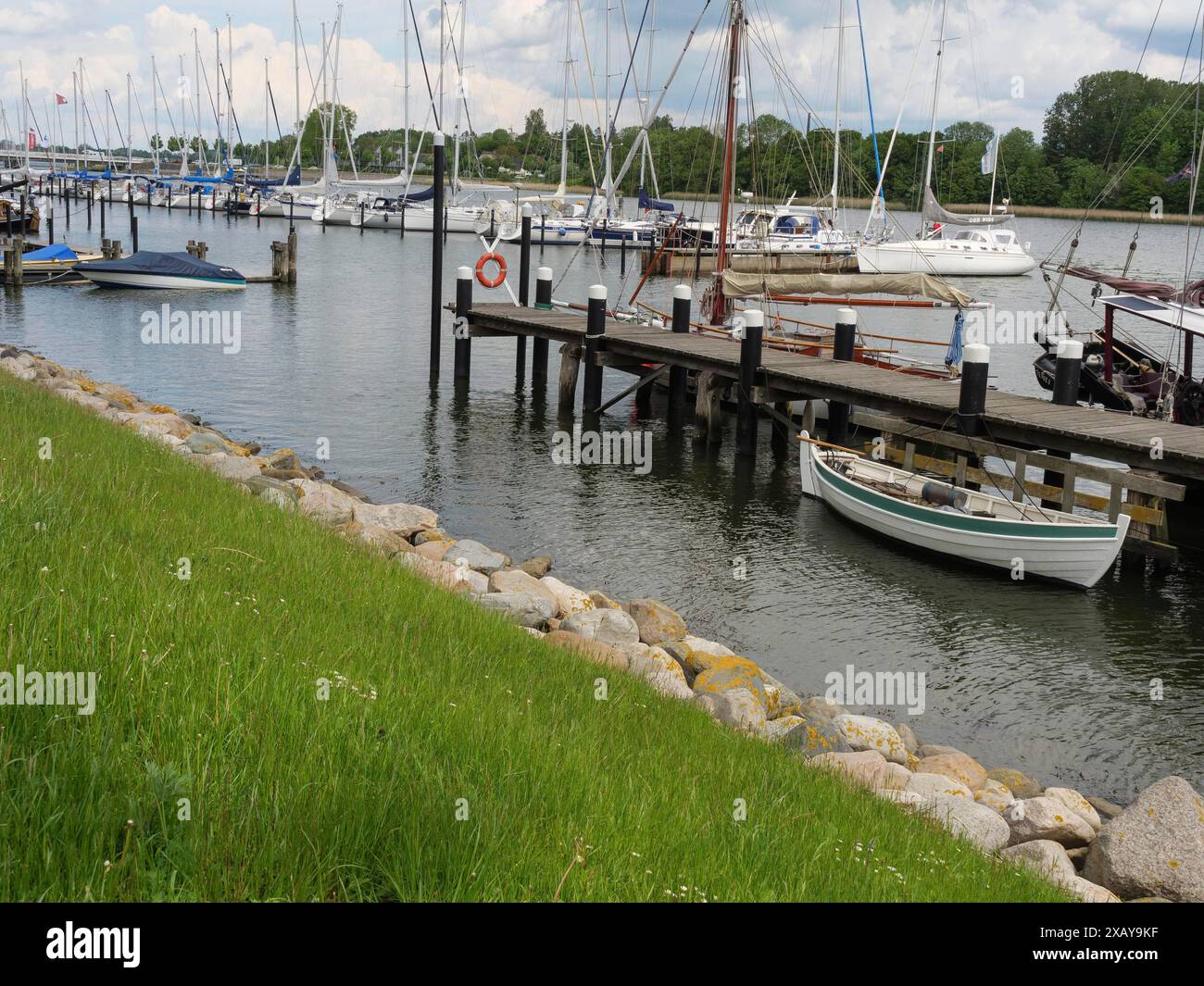 Boats at the dock in a quiet harbour surrounded by grass and a green ...