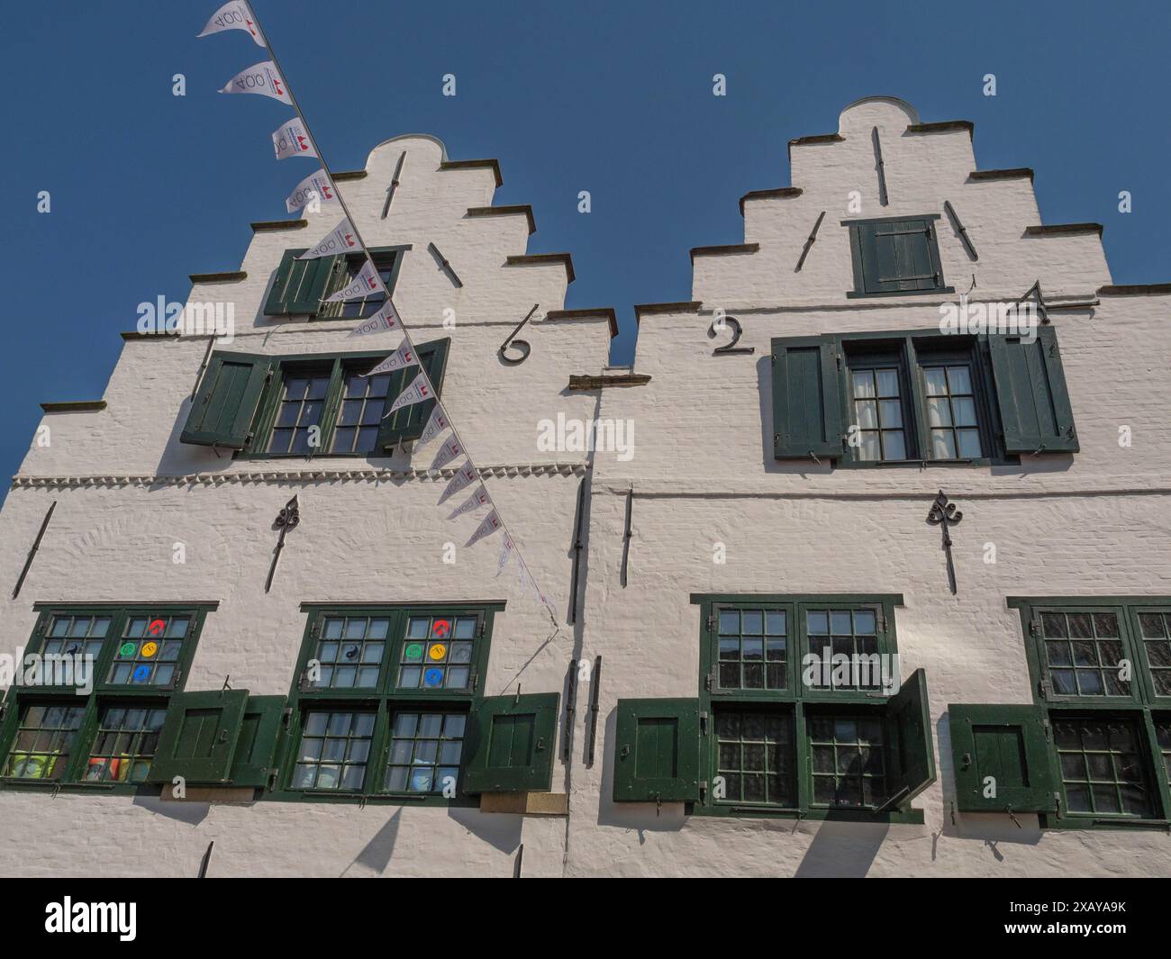 Two historic buildings with green window shutters, decorated with small ...