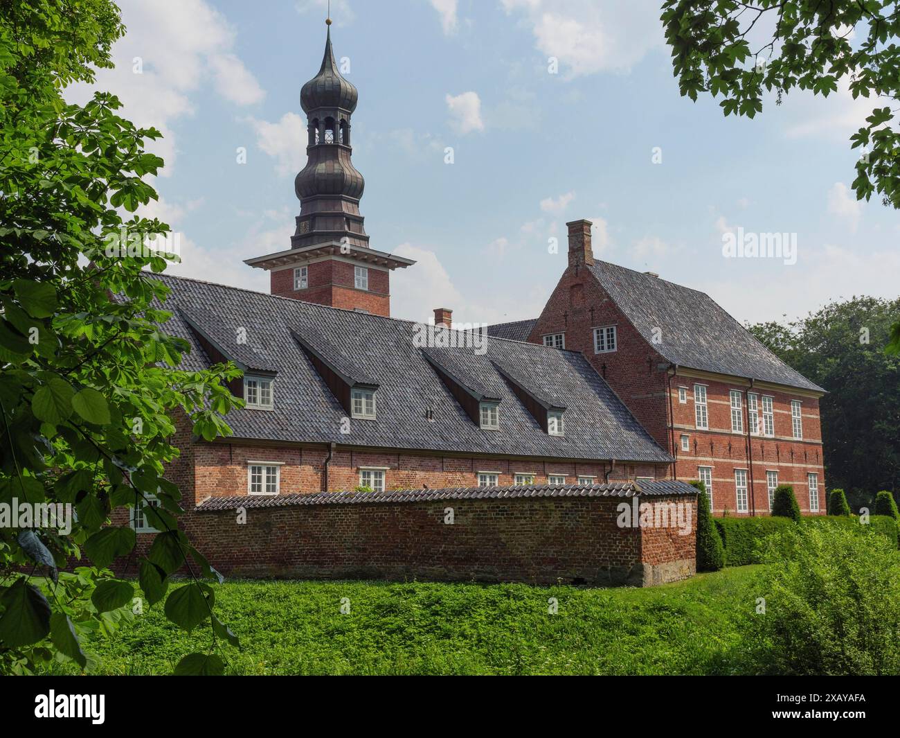 Historic building with church tower and tiled roof surrounded by green ...