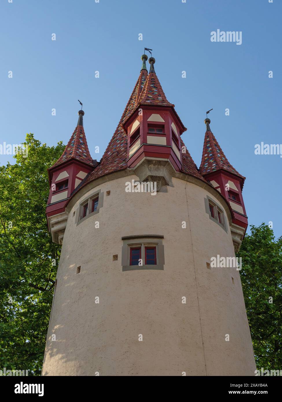 Round tower with red tin towers and surrounding trees under a blue sky ...