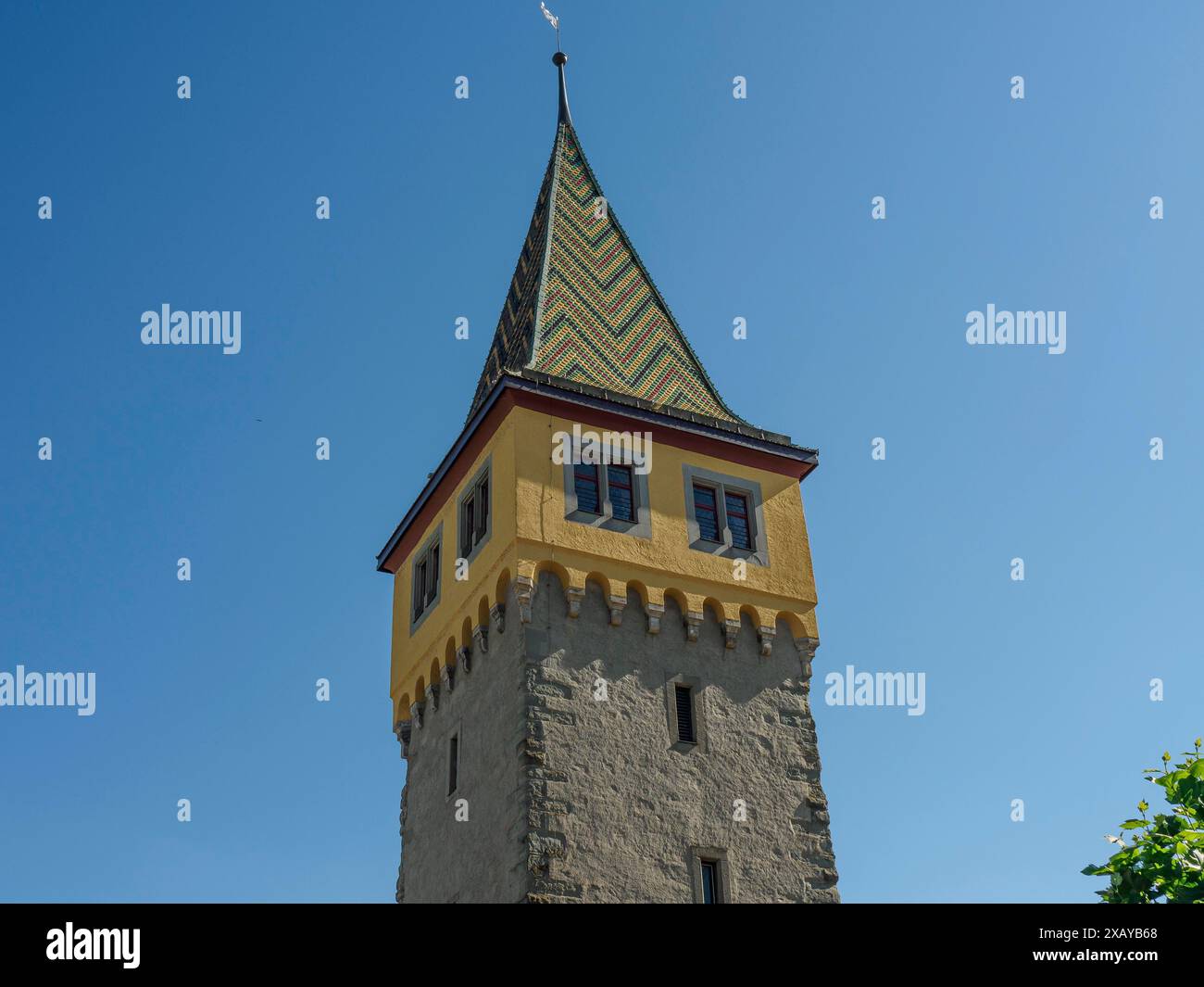 Medieval tower with colourful roof against a clear blue sky, Lindau ...