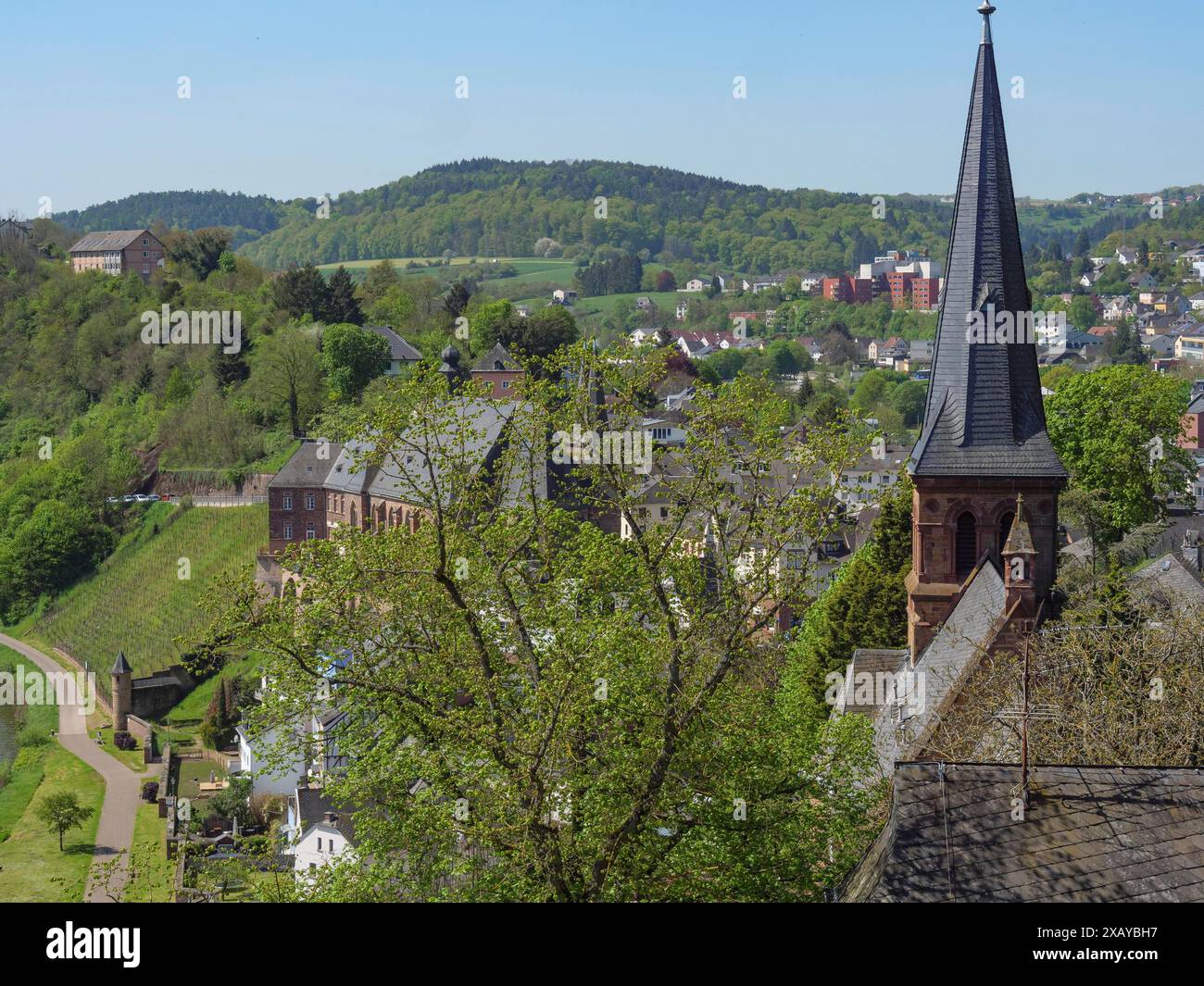 A view over a town with a striking church spire, surrounded by green ...