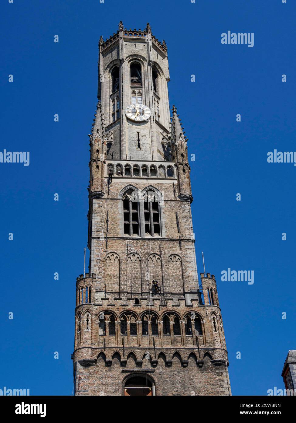 Large medieval brick bell tower with a clock under a bright blue sky ...