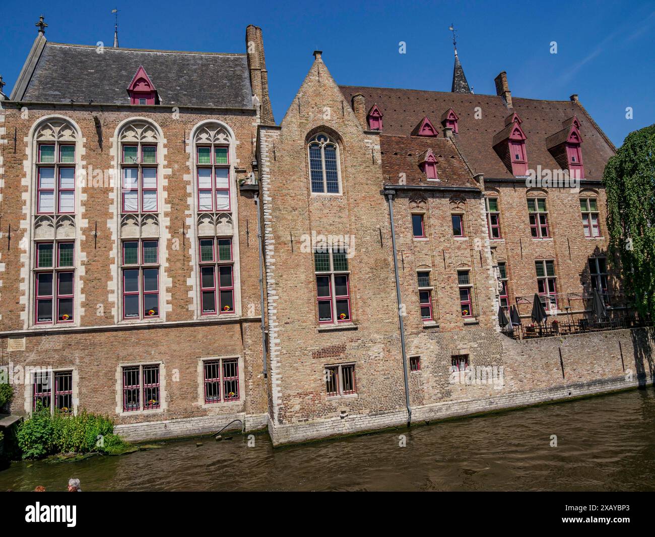 Historic buildings with brick facades along a canal under a bright blue ...