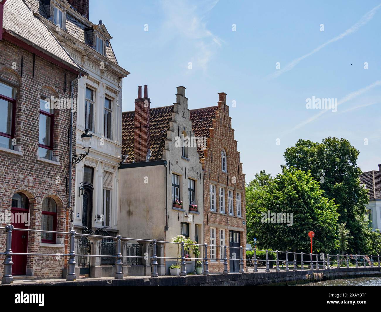 Traditional brick houses along a canal, surrounded by green trees and ...