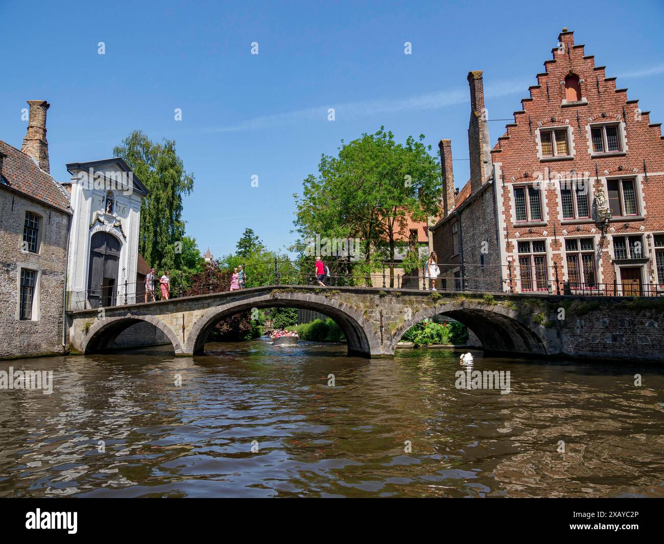 A stone bridge spans a canal, flanked by old buildings and trees, under ...