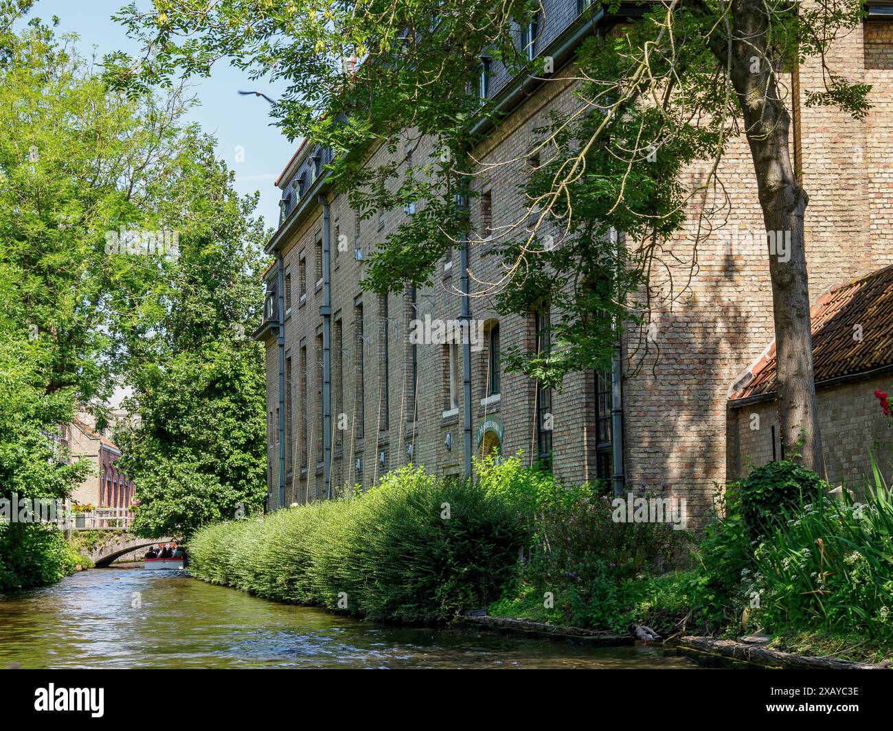 Canal surrounded by historic brick buildings and lush vegetation ...