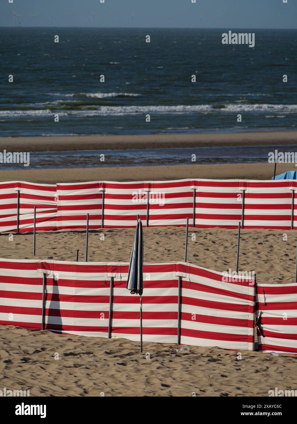 Beach landscape with red and white windbreaks and gentle waves in the ...