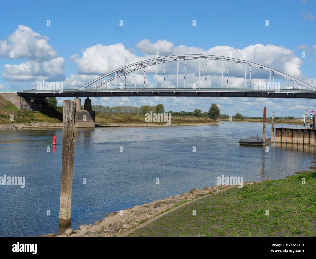 Metal bridge over a river in a clear blue sky with white clouds ...