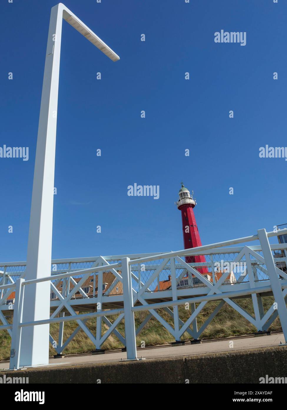 Red lighthouse and white railing in broad daylight with clear blue sky ...