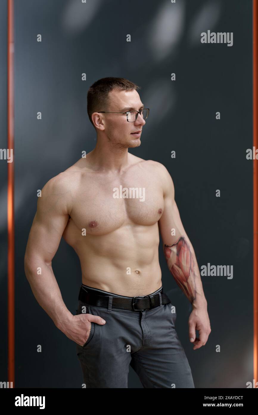 Fit man showing muscle definition in a casual setting Stock Photo - Alamy