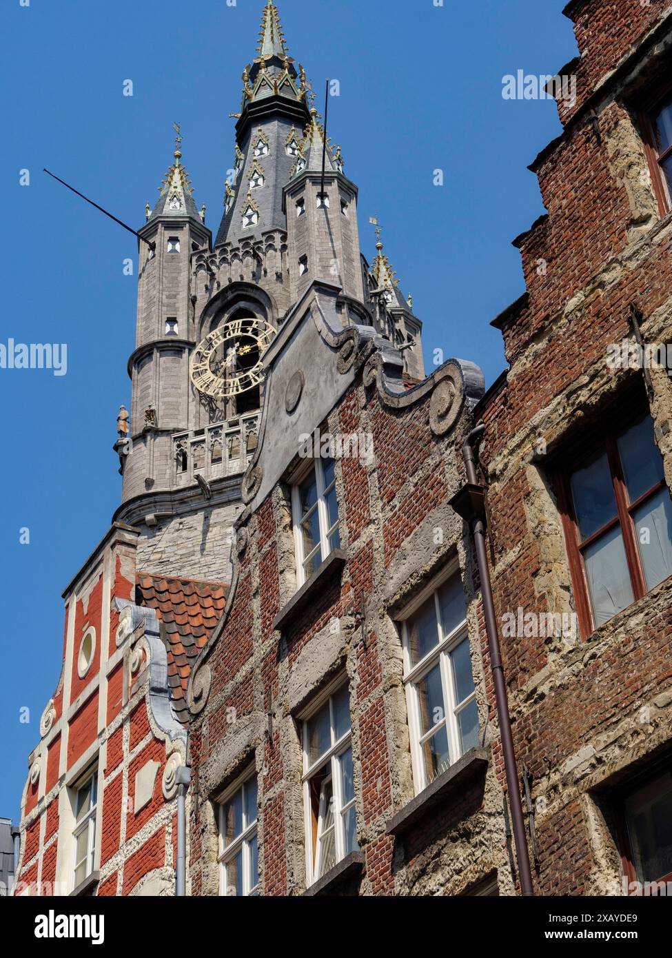 Gothic bell tower with clock and neighbouring brick buildings under a ...