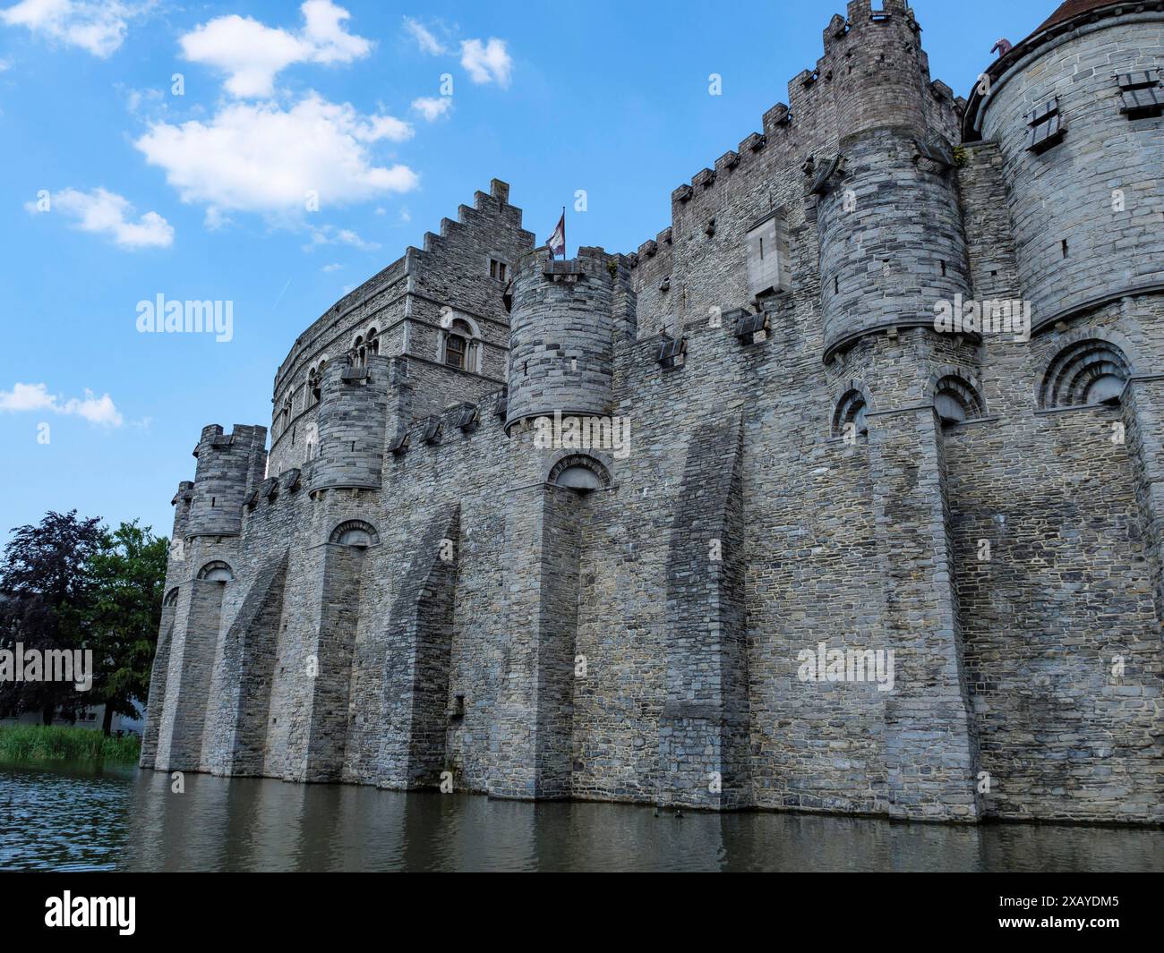 Medieval castle with fortification towers by a river under a blue sky ...