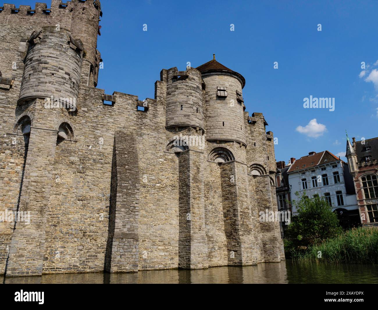 A well-preserved medieval castle with massive stone walls and a moat, under a clear sky, gent ...