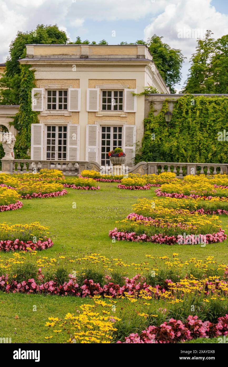 Flower beds in the garden of a historic building with shutters and ivy ...