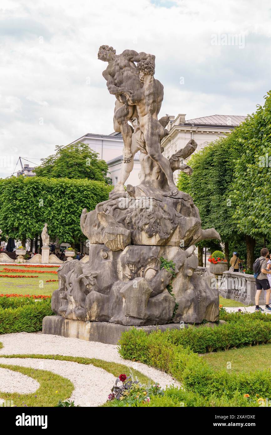 A detailed stone statue in a well-tended garden with trees in the ...