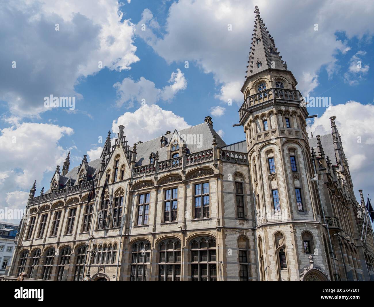 Large historic building with Gothic architecture and towers under a blue sky with clouds, Ghent ...