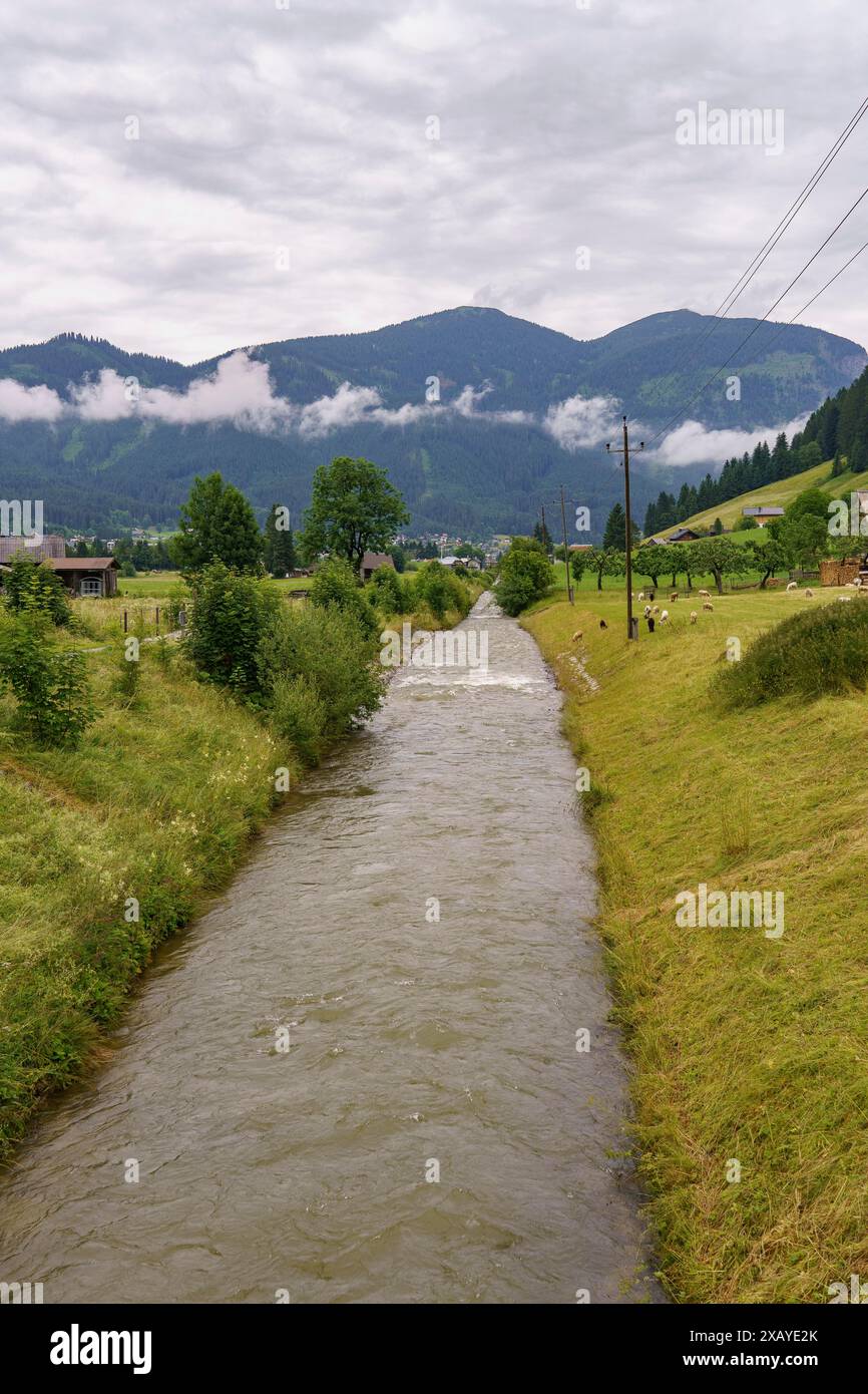 River flows through green meadows and villages, surrounded by mountains ...