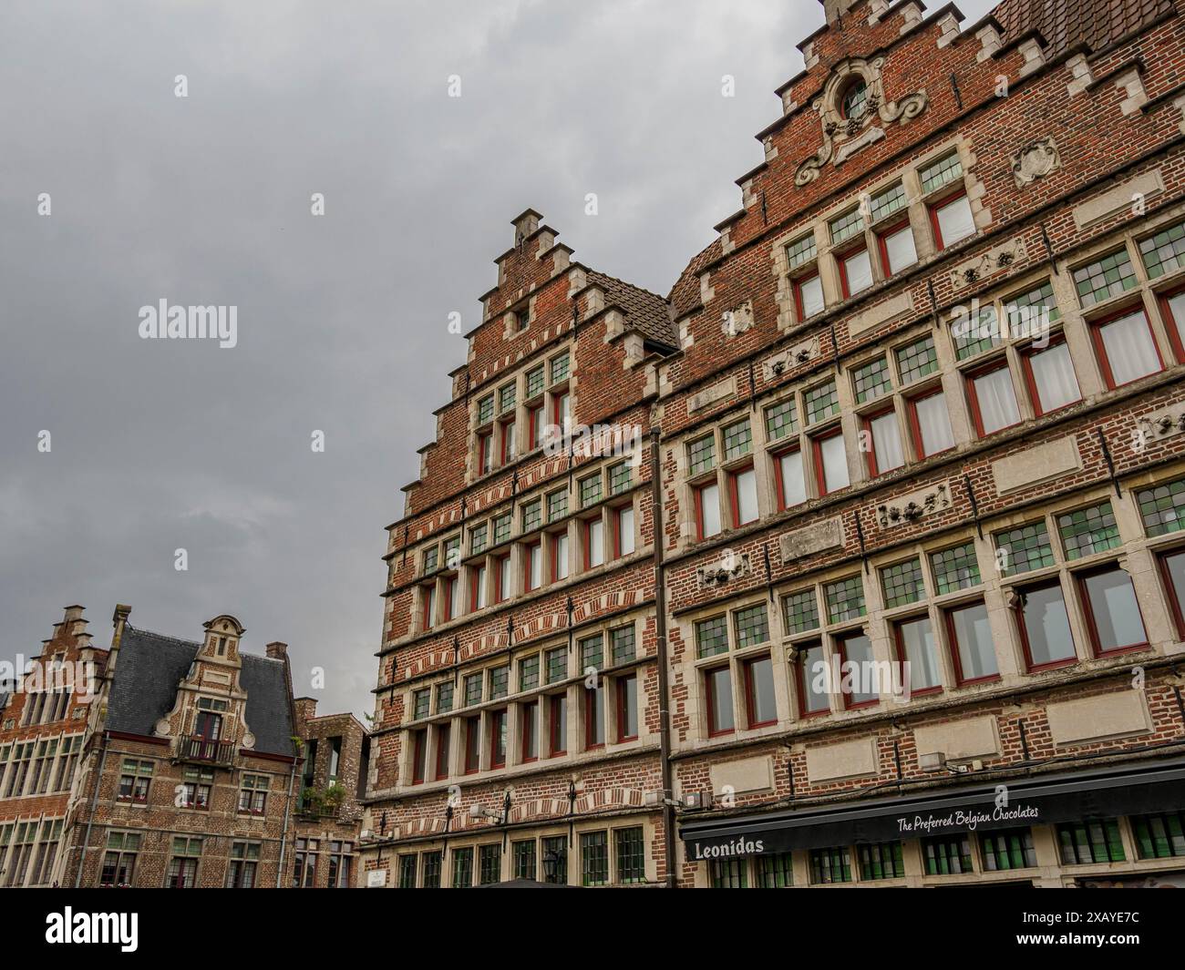 Row of historic brick buildings with numerous windows under a dark sky ...