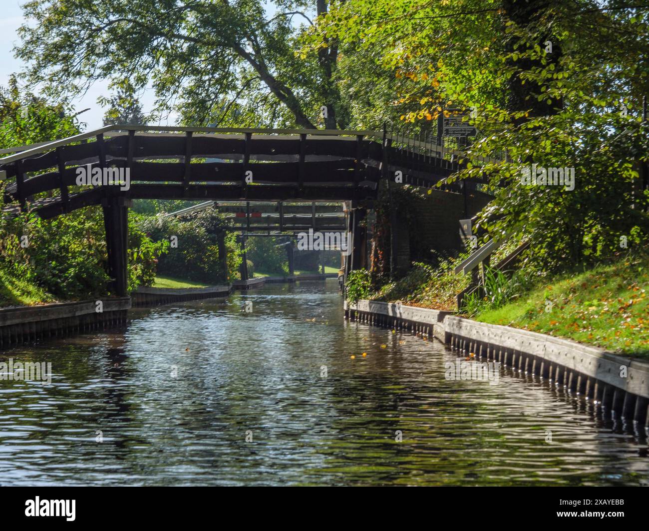 Wooden bridge over a quiet canal surrounded by trees in a peaceful ...