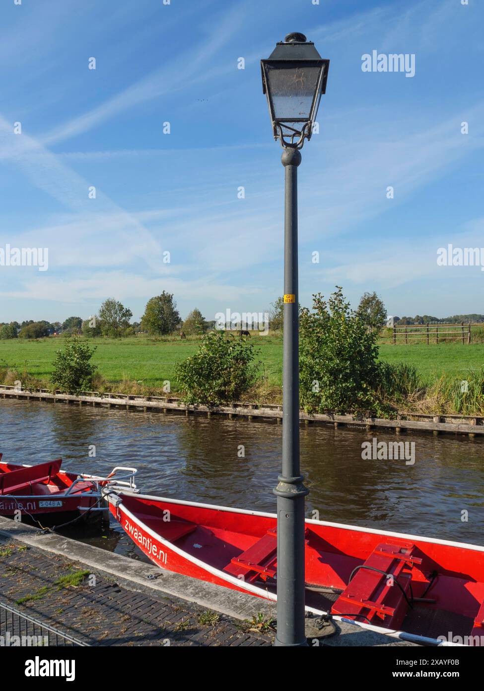 Red boats in the canal under an old lantern, with meadows and trees in ...