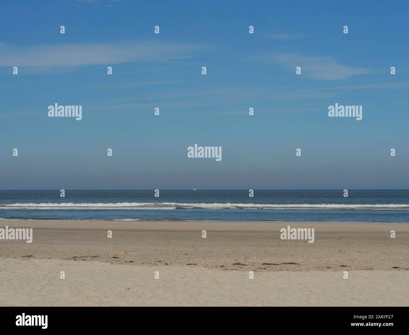A calm beach with gentle waves and a clear blue sky above, langeoog ...