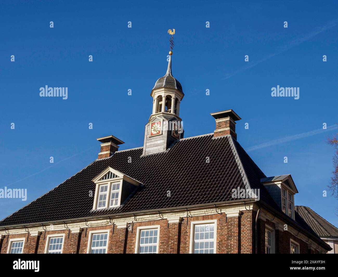 Historic clock tower spire on a brick building under a clear blue sky ...