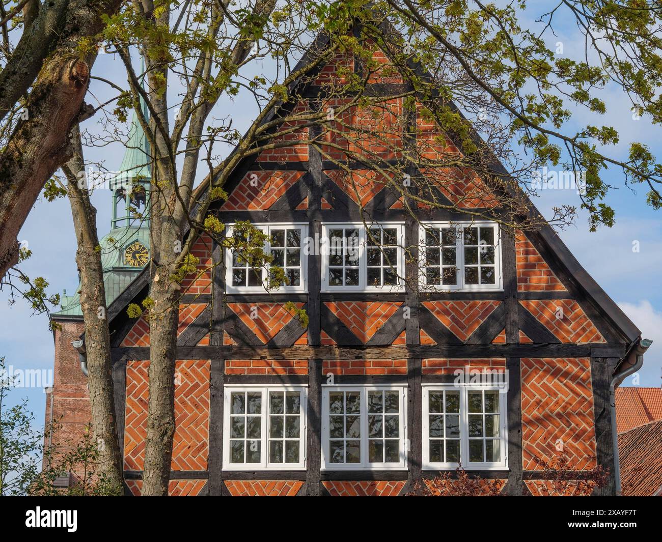 The picture shows a half-timbered house with red bricks, surrounded by ...