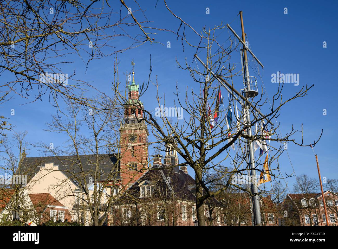 Building with towers and a mast with flags, surrounded by trees under a ...