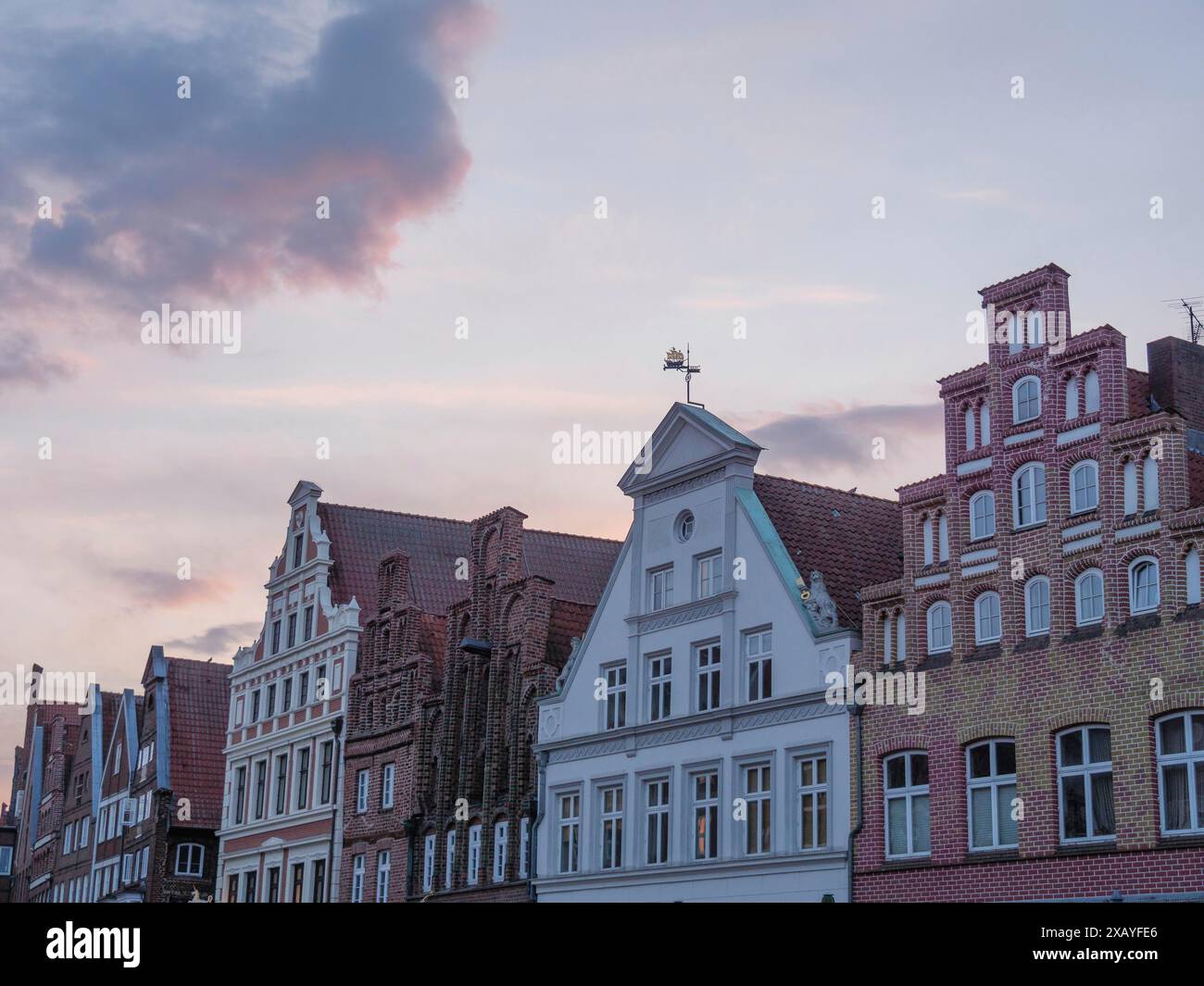 Row of ornate, historic buildings with red roofs at sunset, lueneburg ...