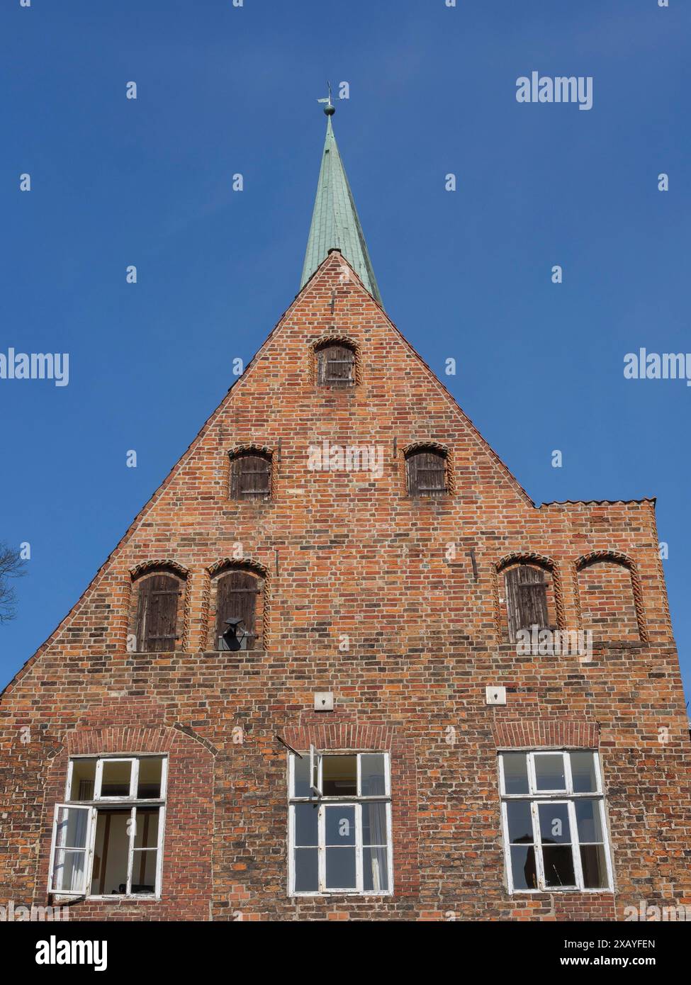 Brick building with a striking gable front and a spire, large windows ...