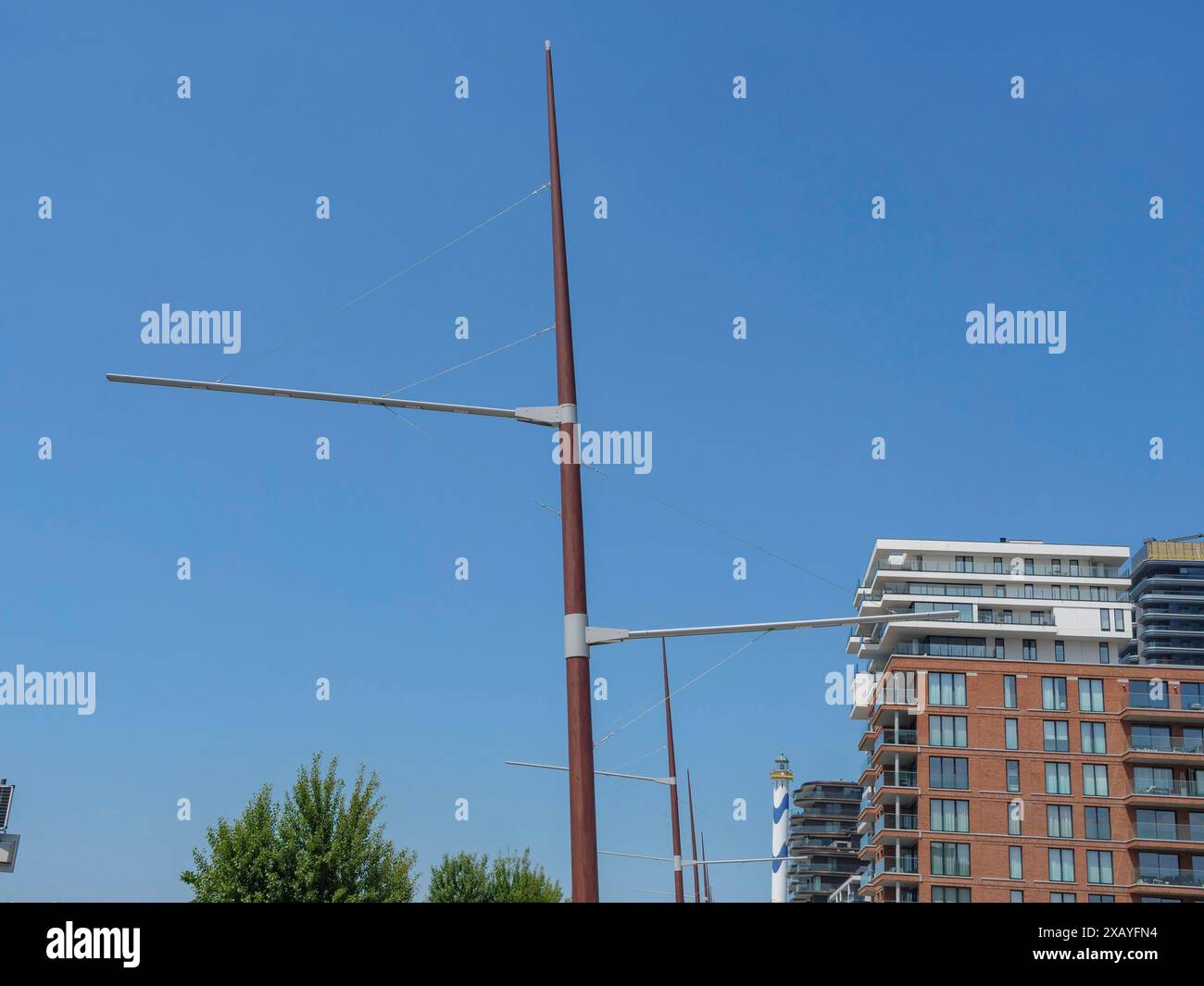 Large mast in front of modern skyscrapers under a clear blue sky ...