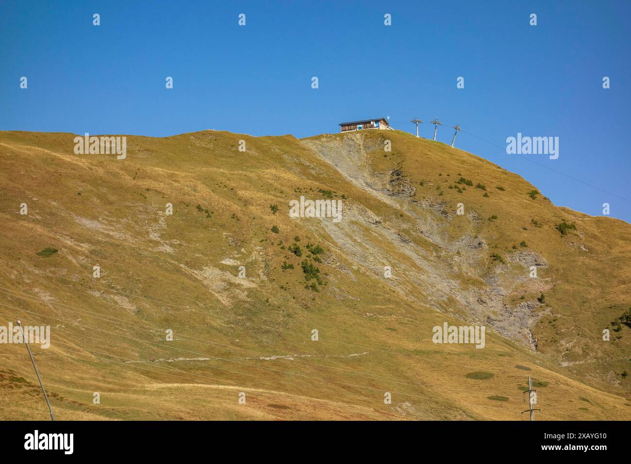 Extensive mountain landscape with a hut on a hill, crossed by a cable ...