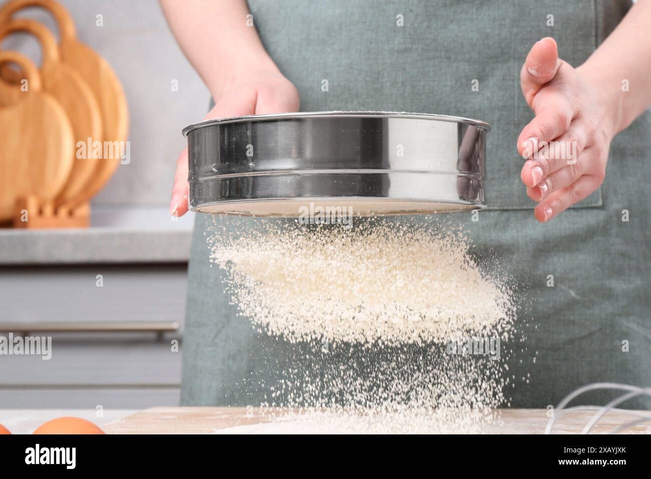 Woman sieving flour at table in kitchen, closeup Stock Photo - Alamy