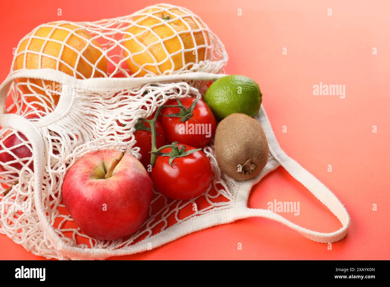 String bag with different vegetables and fruits on red background ...
