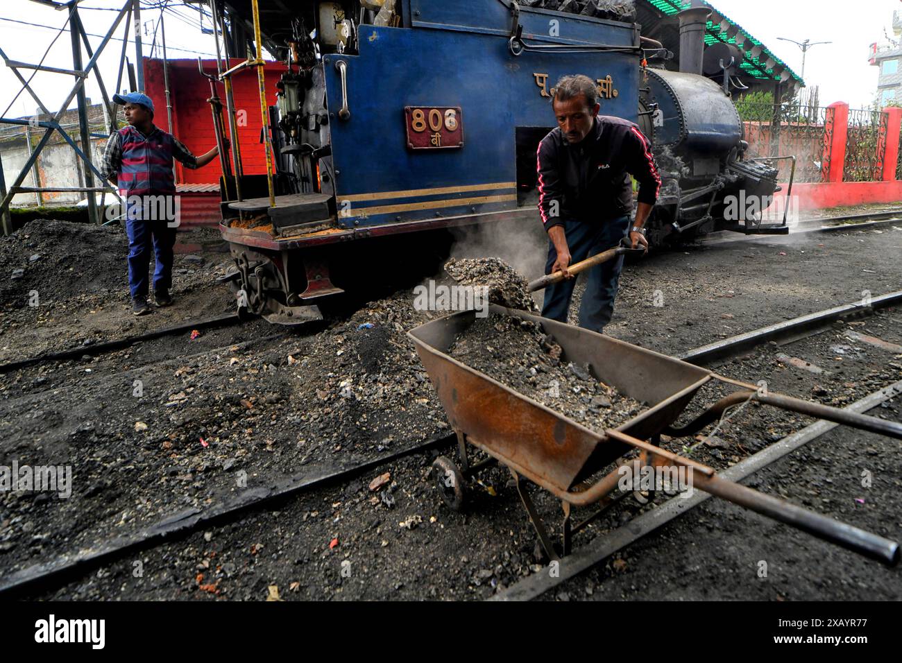 Railway employees load coal into a steam engine of Toy Train at Ghum ...