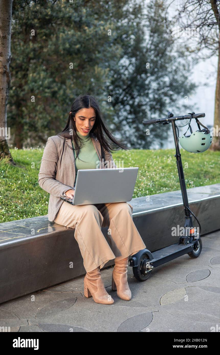vertical businesswoman is seated on a bench next to her electric ...