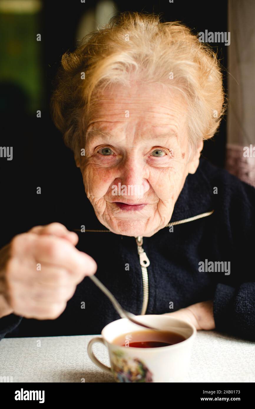 An elderly woman sipping tea, captured in a detailed portrait that ...