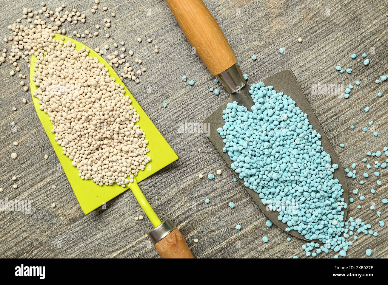 Gardening shovels with granular fertilizer on grey wooden background ...