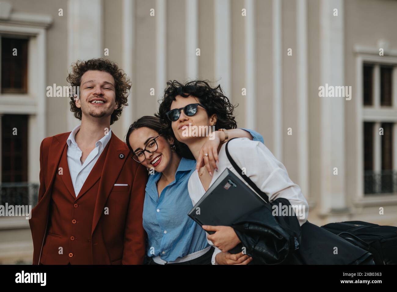Three happy friends posing together and smiling outdoors in front of a ...