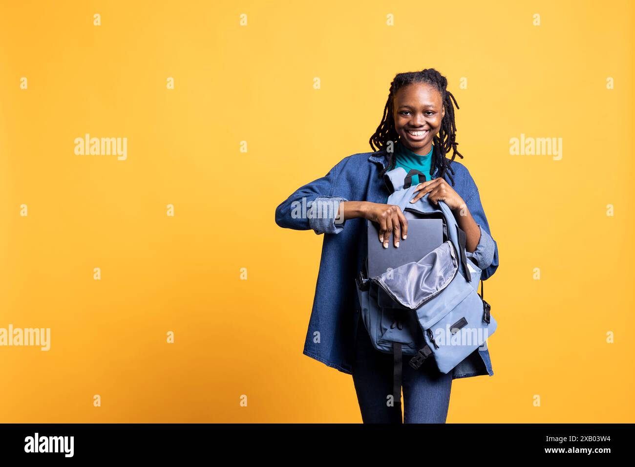 Portrait of cheerful woman putting laptop in backpack, preparing to go ...