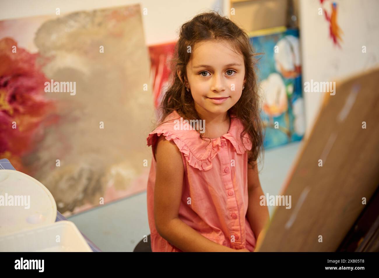 Young girl participating in an art class, painting on canvas with a ...