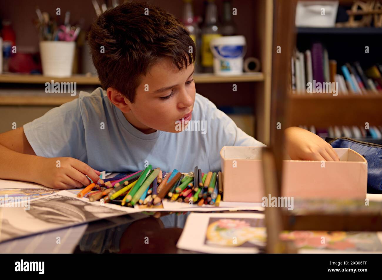 Young boy attentively drawing at an art class table filled with colored ...