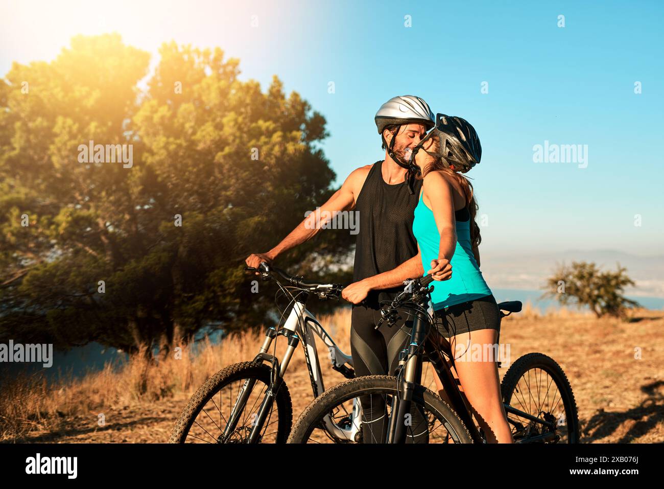 Man, woman or cycling with bicycle and kiss in countryside for exercise, romance with workout in ...