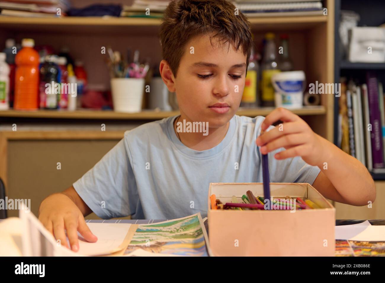 Boy drawing with colored pencils in an art class workshop, focusing on ...