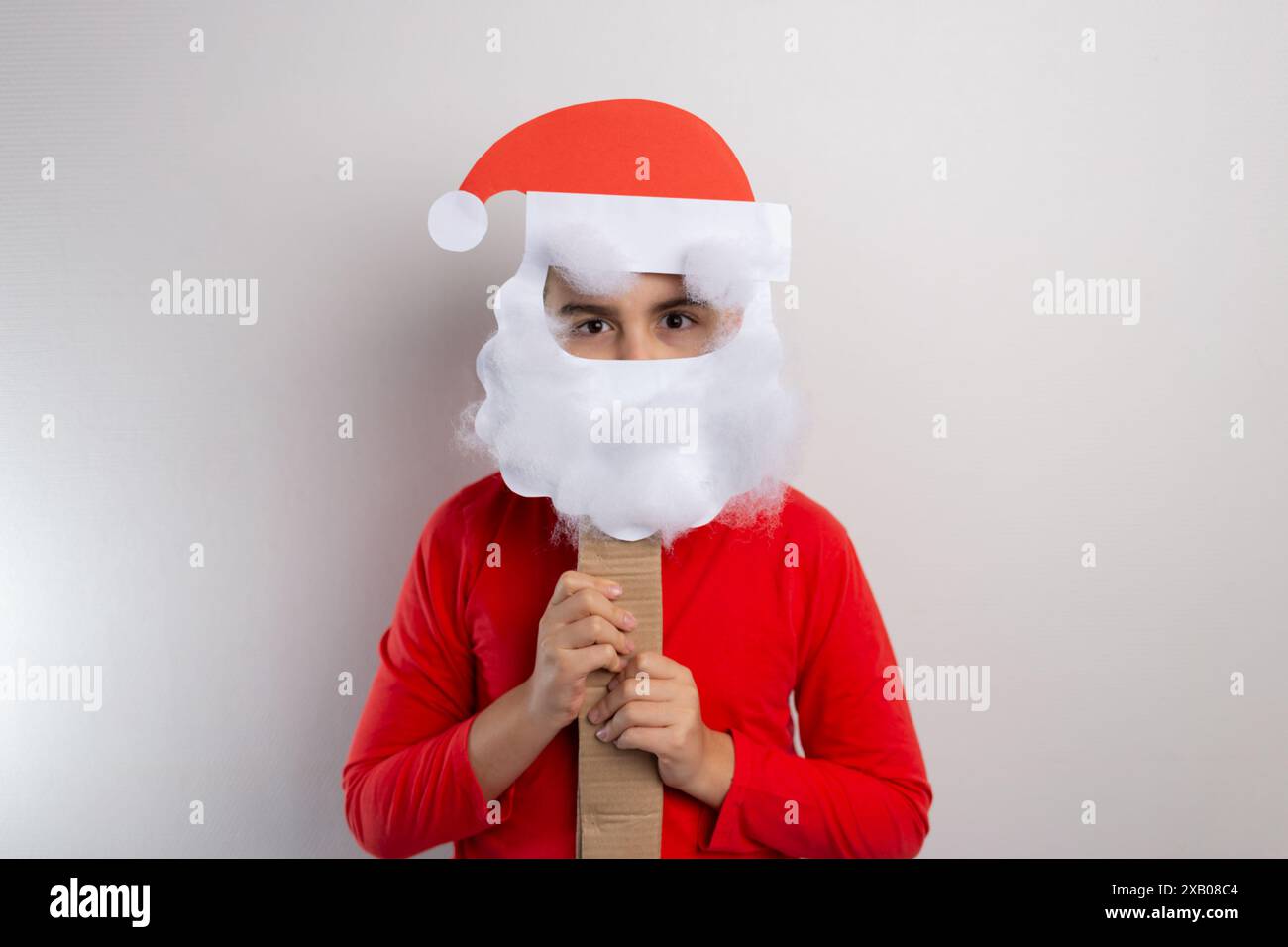 a boy wearing a paper craft Santa hat and beard, disguise New Year mask ...